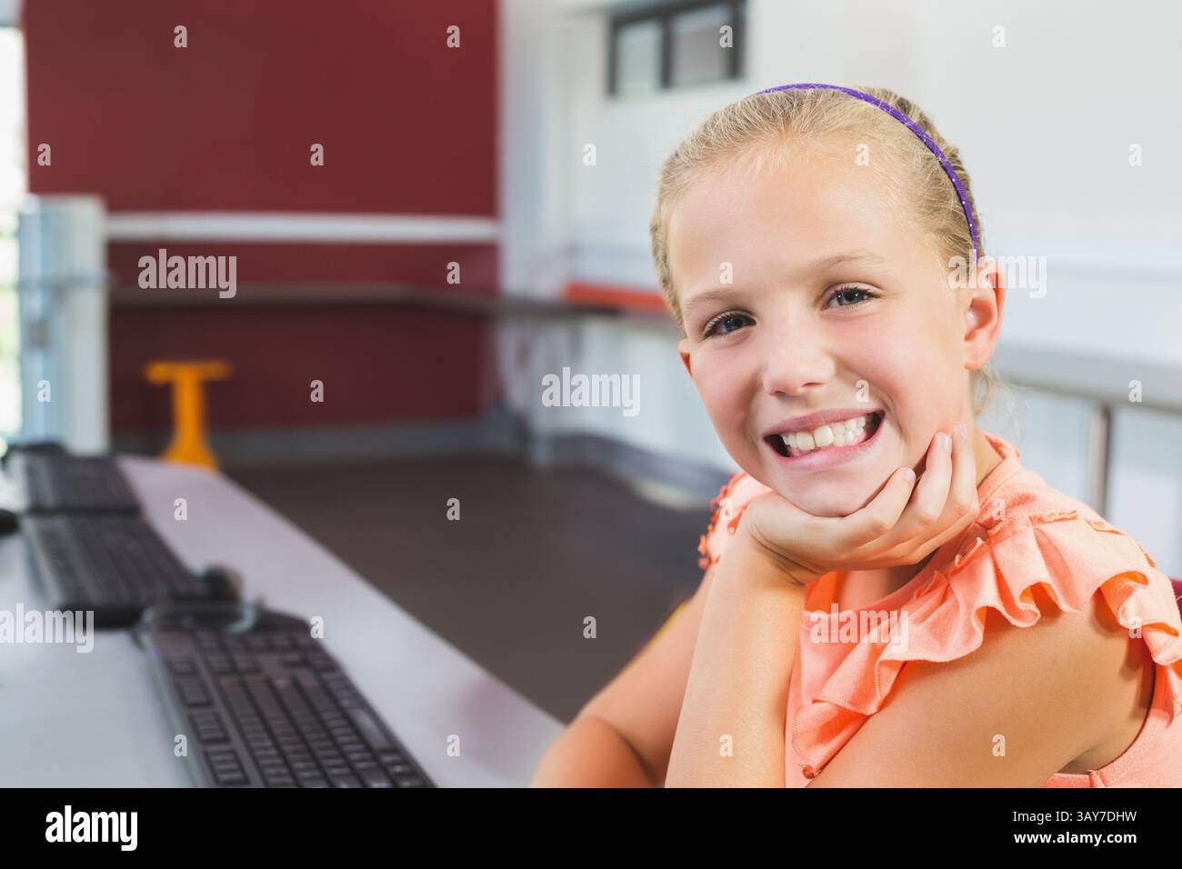 School-age girl typing on keyboard in computer lab wearing purple ...