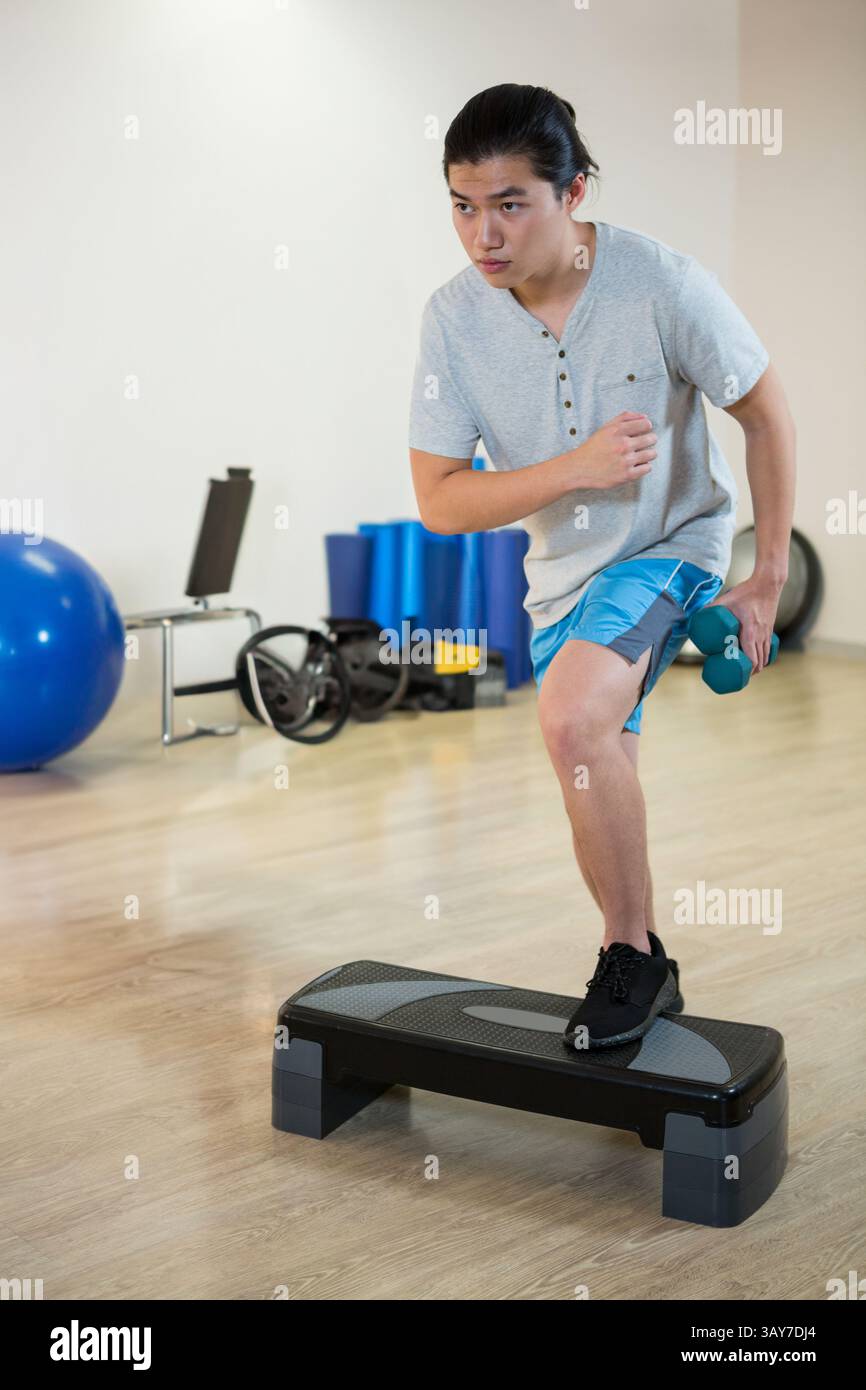 Asian young adult woman stepping onto aerobic step in indoor fitness ...