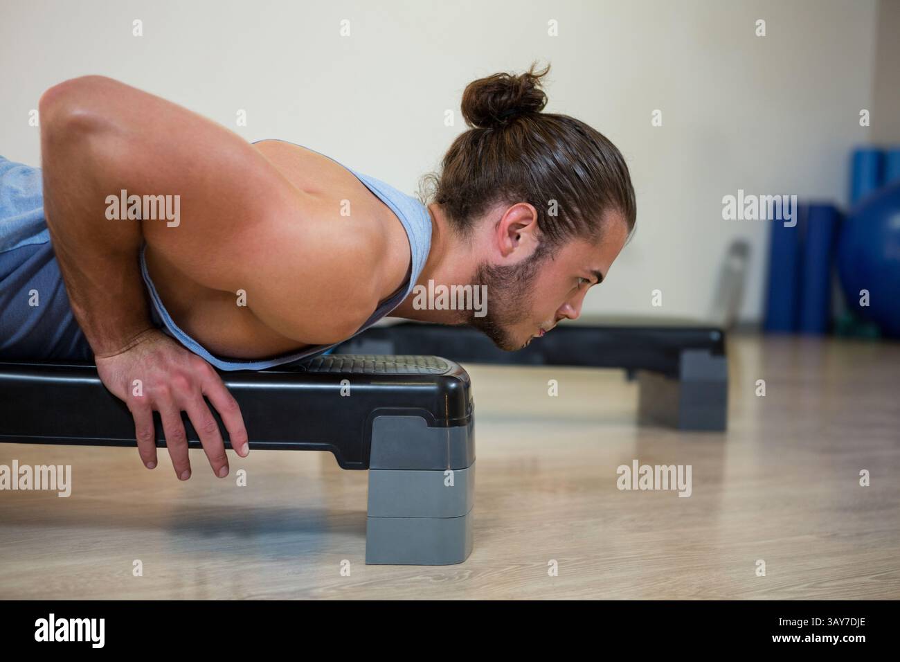 Man performing push?up on step platform in gym with foam rollers ...