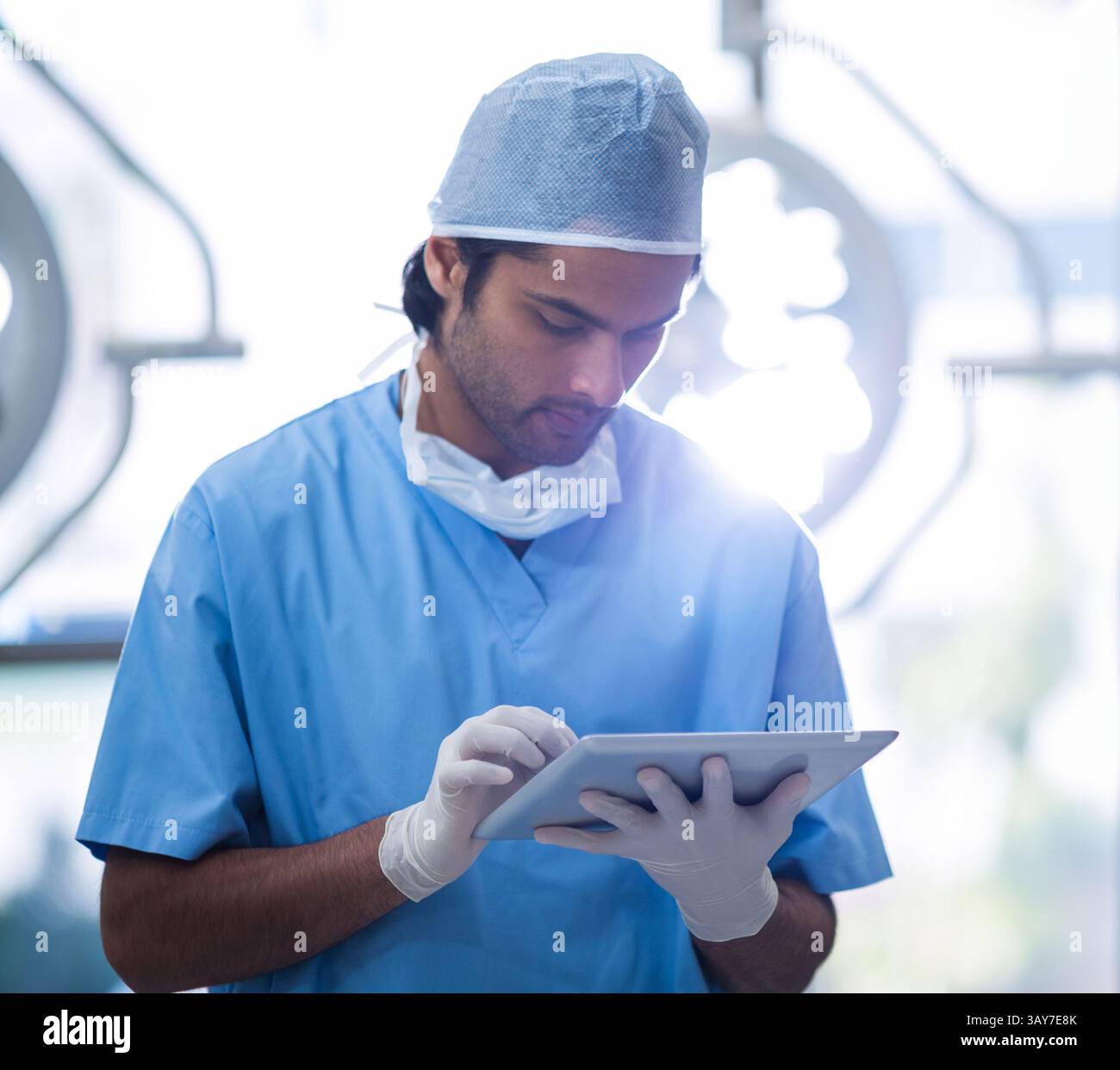 Asian male surgeon tapping tablet screen in operating room, with ...