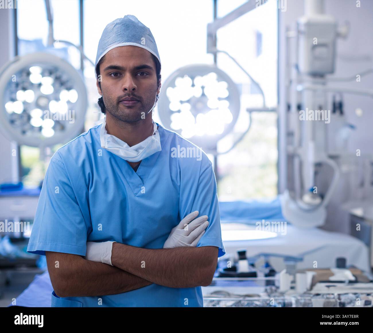 Asian male surgeon crossing arms in operating room, with surgical ...