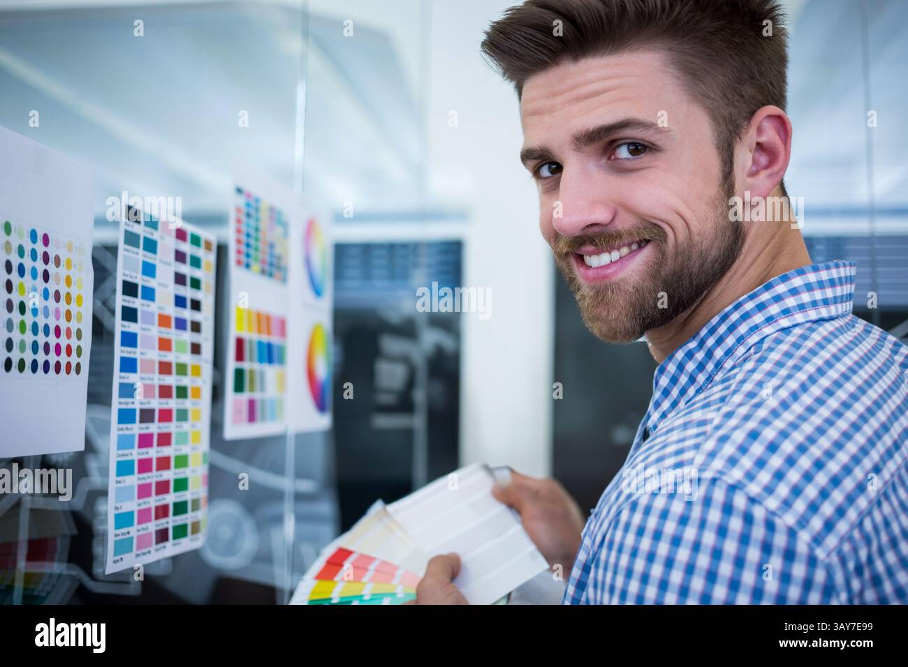 Man standing before glass panel with color charts holding swatch fan ...