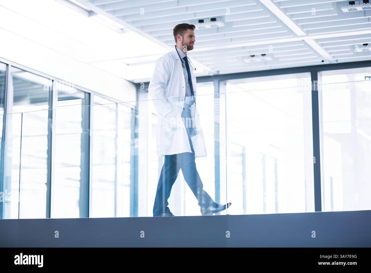 Young male doctor walking in hospital corridor, with stethoscope glass ...