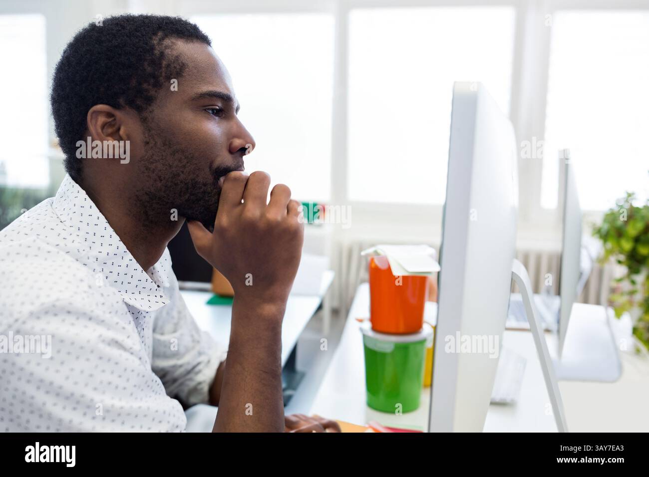 African American man sitting at office desk, gazing at monitor with ...
