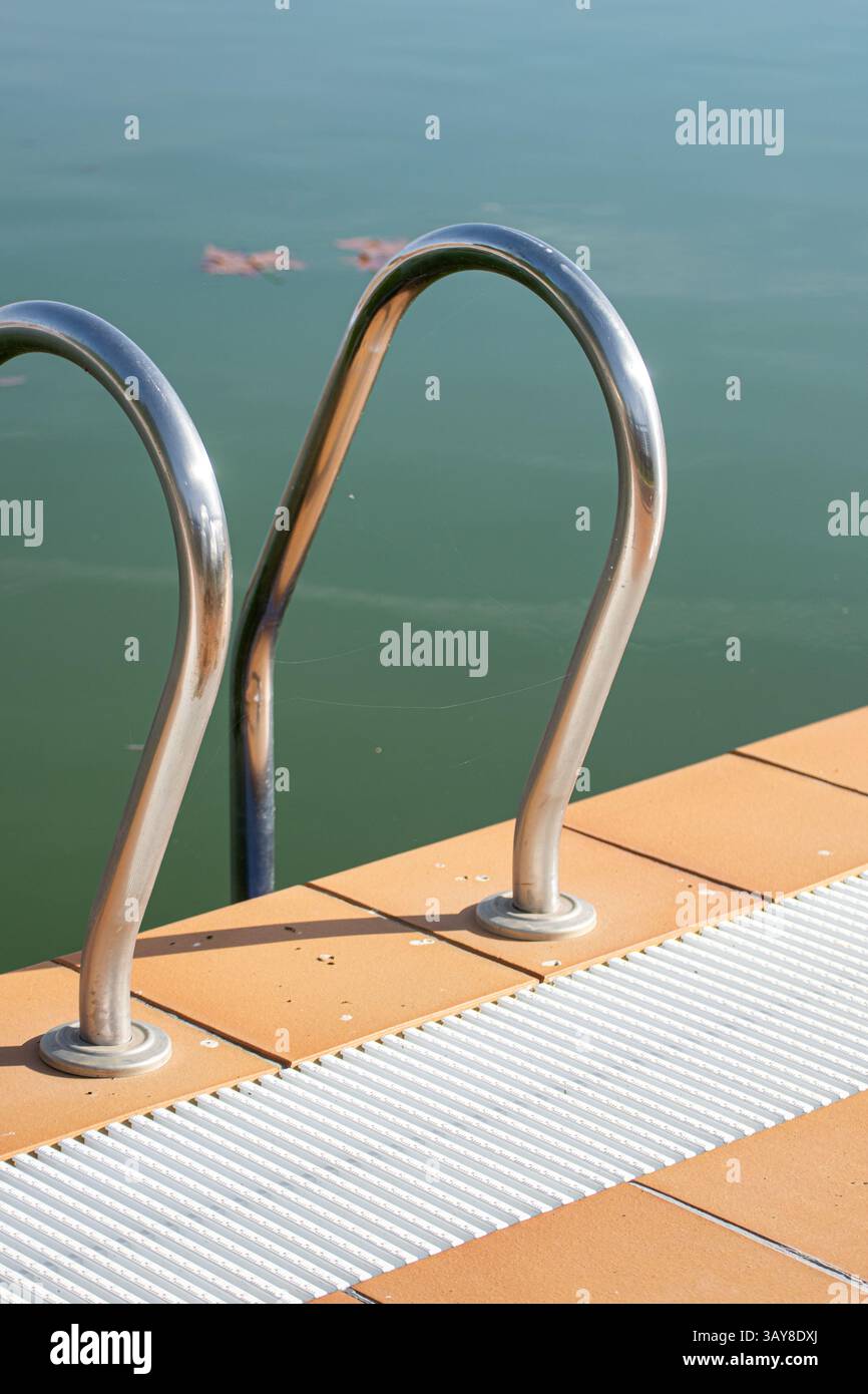 shiny metal handrails of a swimming pool ladder, detail with visible ...