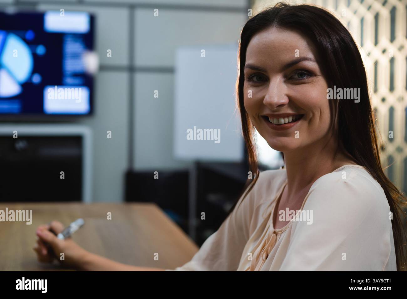 Businesswoman sitting at meeting table in office smiling with monitor ...