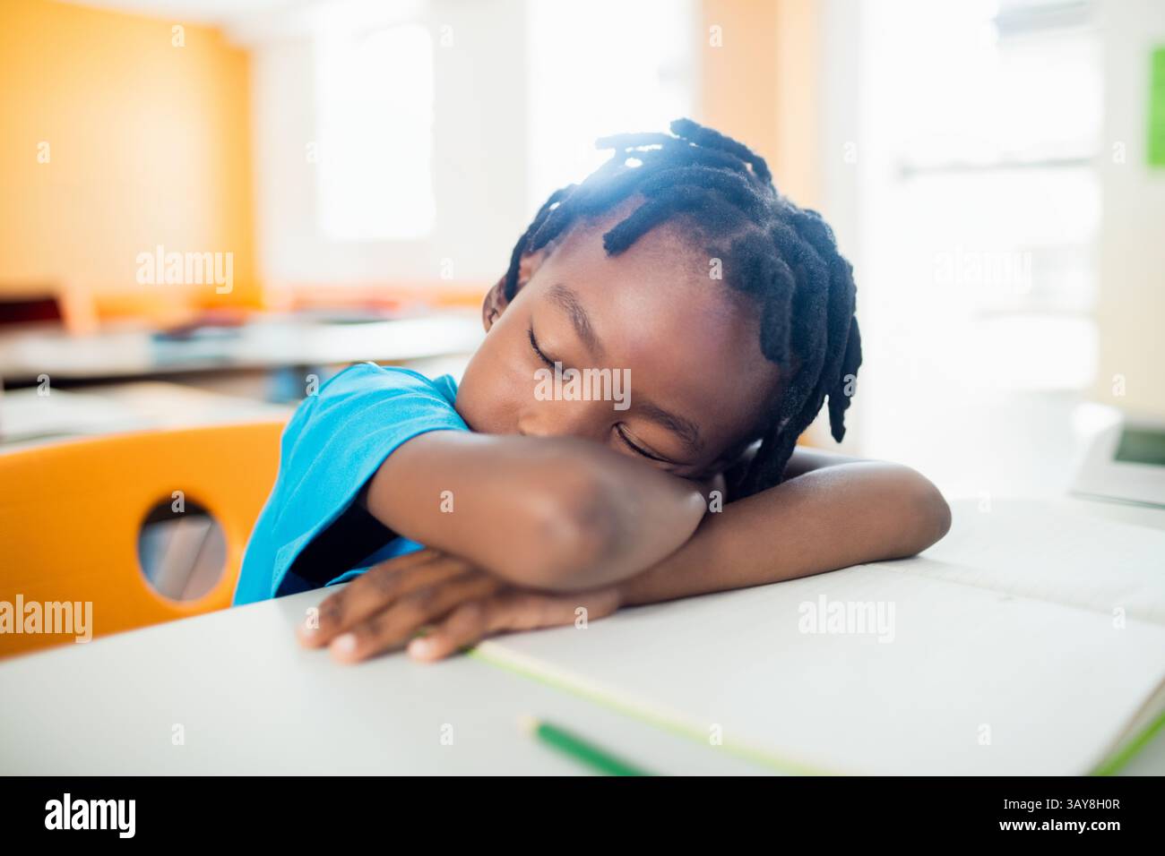 African American child boy sleeping on school desk in classroom, with ...