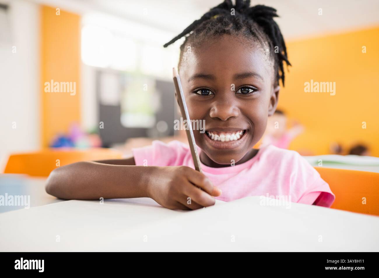 African American girl writing on paper at desk in elementary school ...