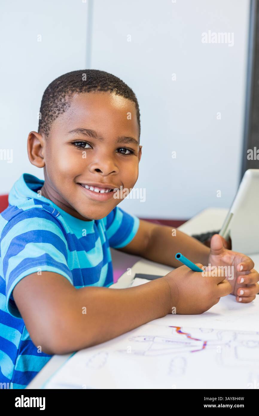 African American boy child drawing with blue pencil on paper in ...