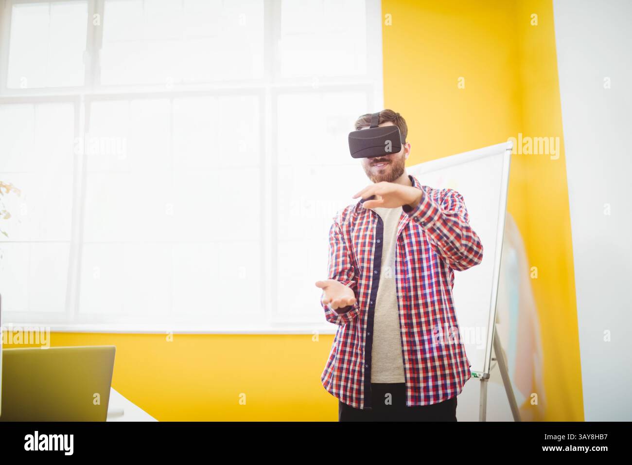 Man standing in bright yellow training room using VR headset ...