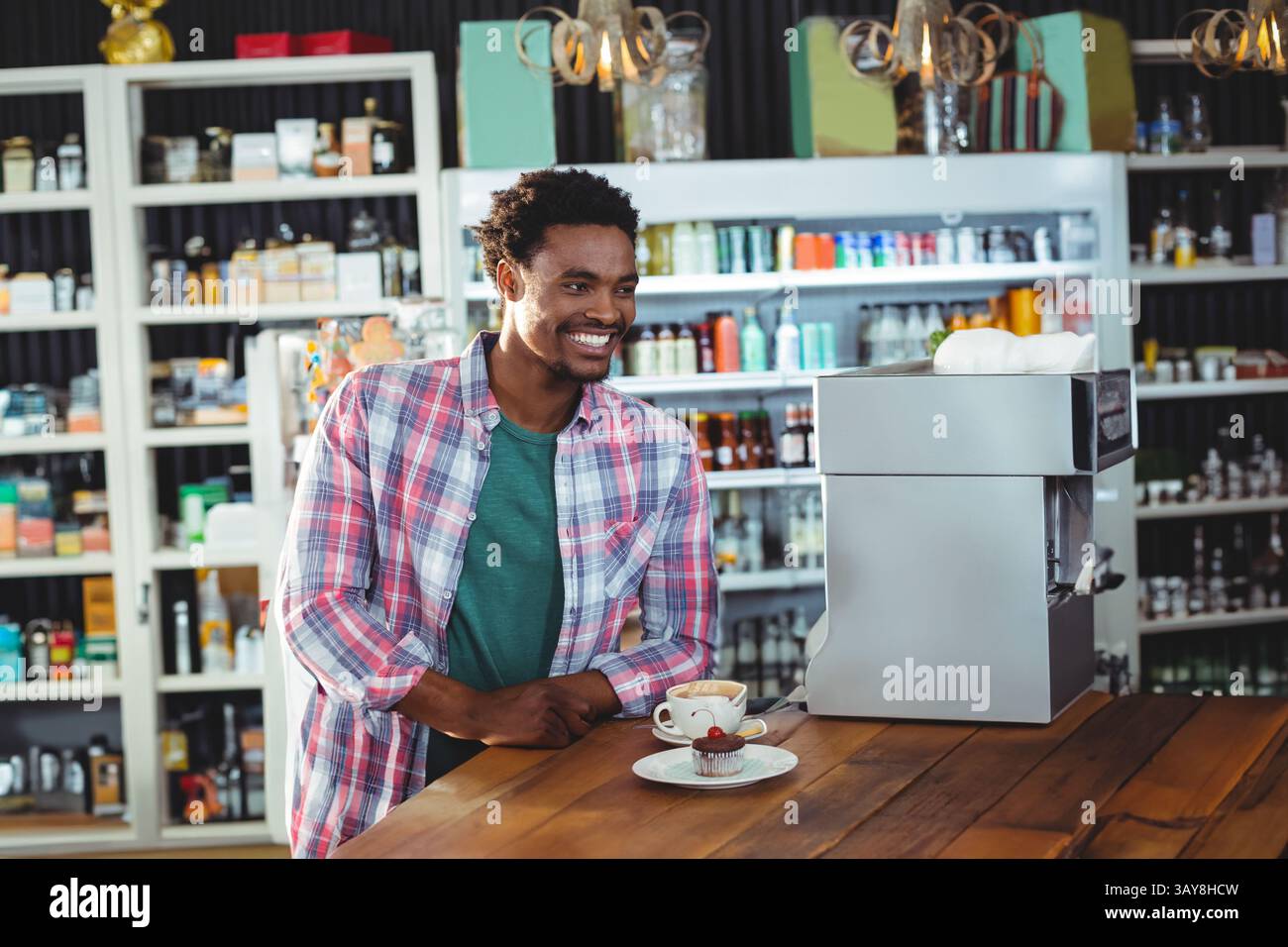 Young African American man leaning on counter in coffee shop, smiling ...