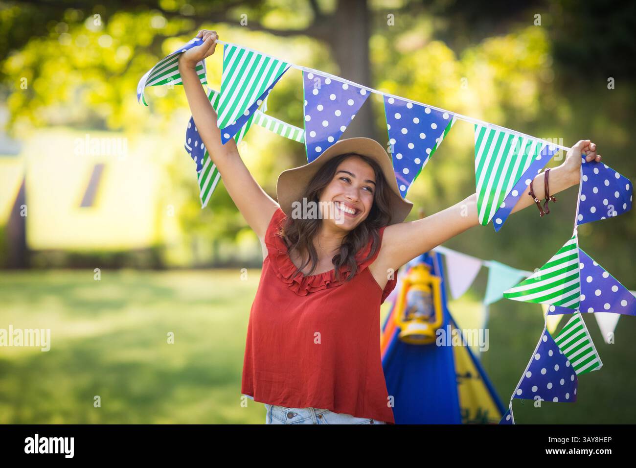 Young woman raising triangular flags in backyard garden, with blue play ...
