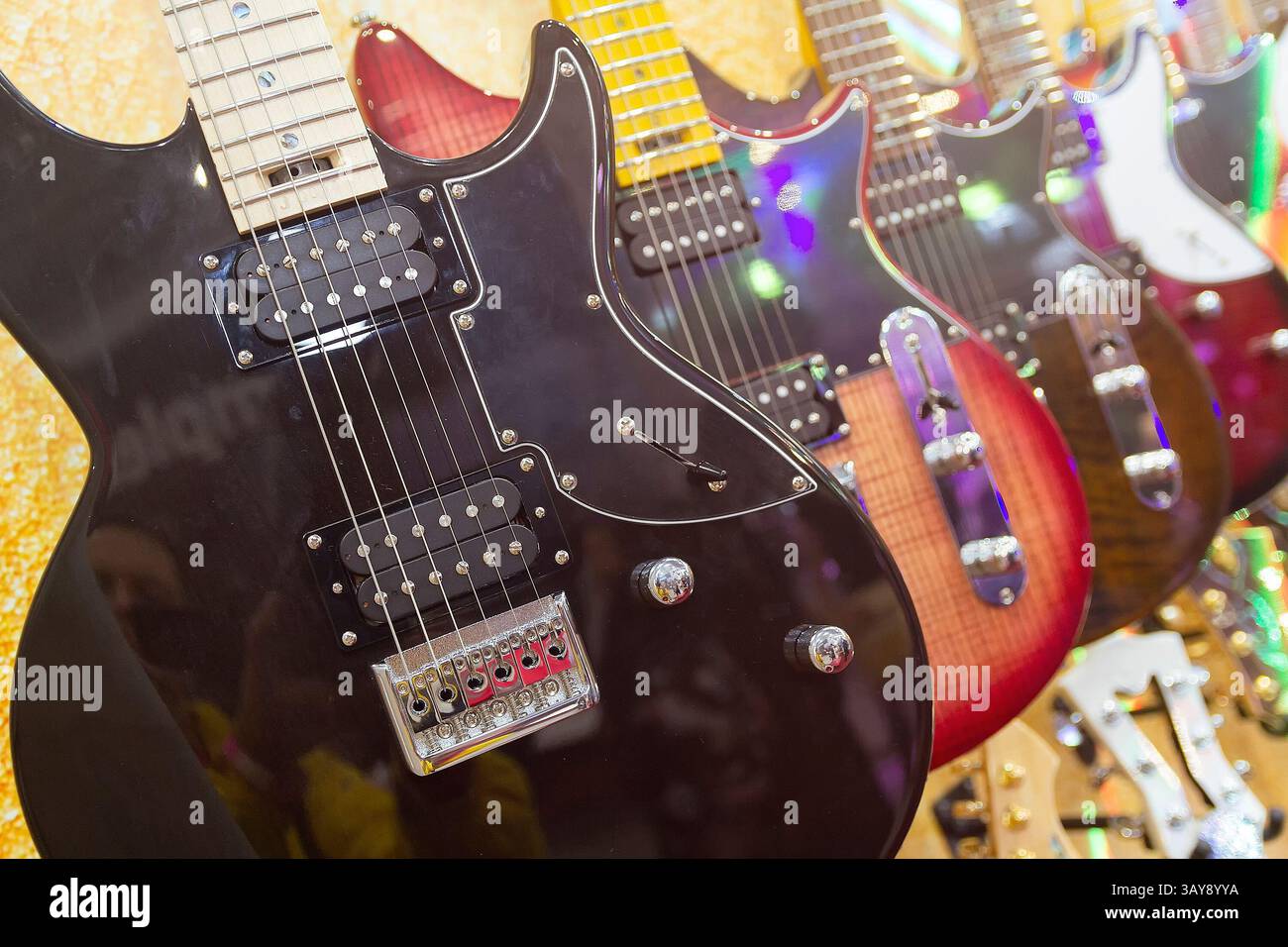 A row of different electric guitars hanging in the music store close-up ...