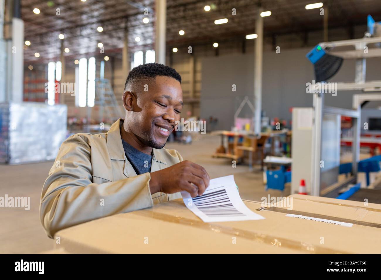 African American man peeling barcode label at warehouse packing station ...