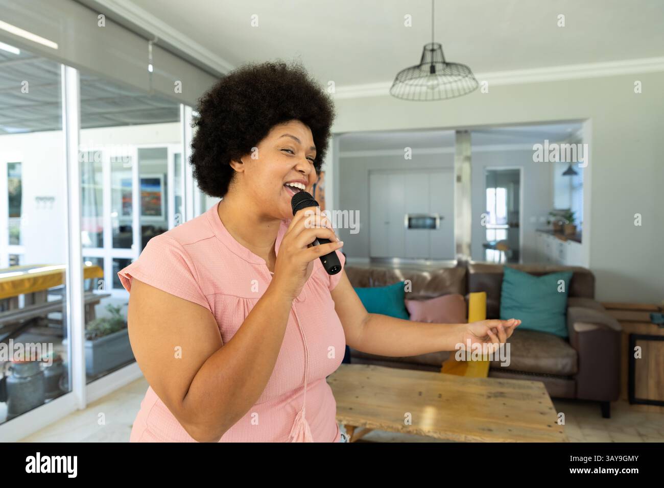 Woman singing into wireless microphone in living room with wooden ...