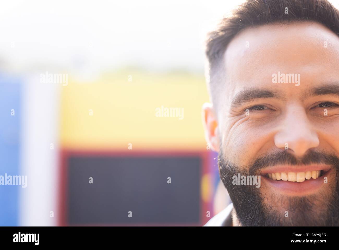 Young man smiling broadly in front of colorful painted mural outdoors ...