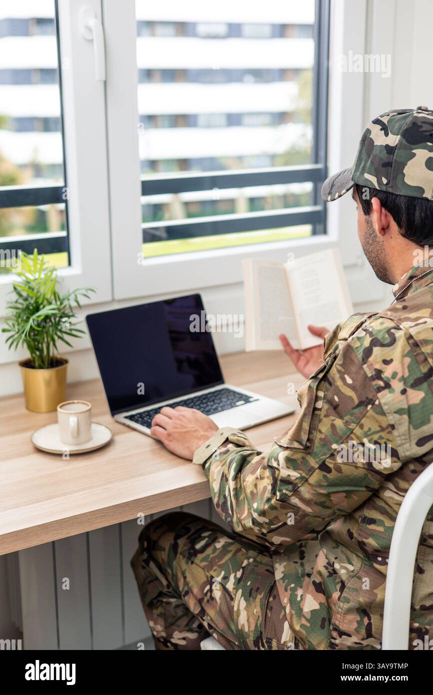 vertical Military man in camouflage uniform sitting at desk, using ...