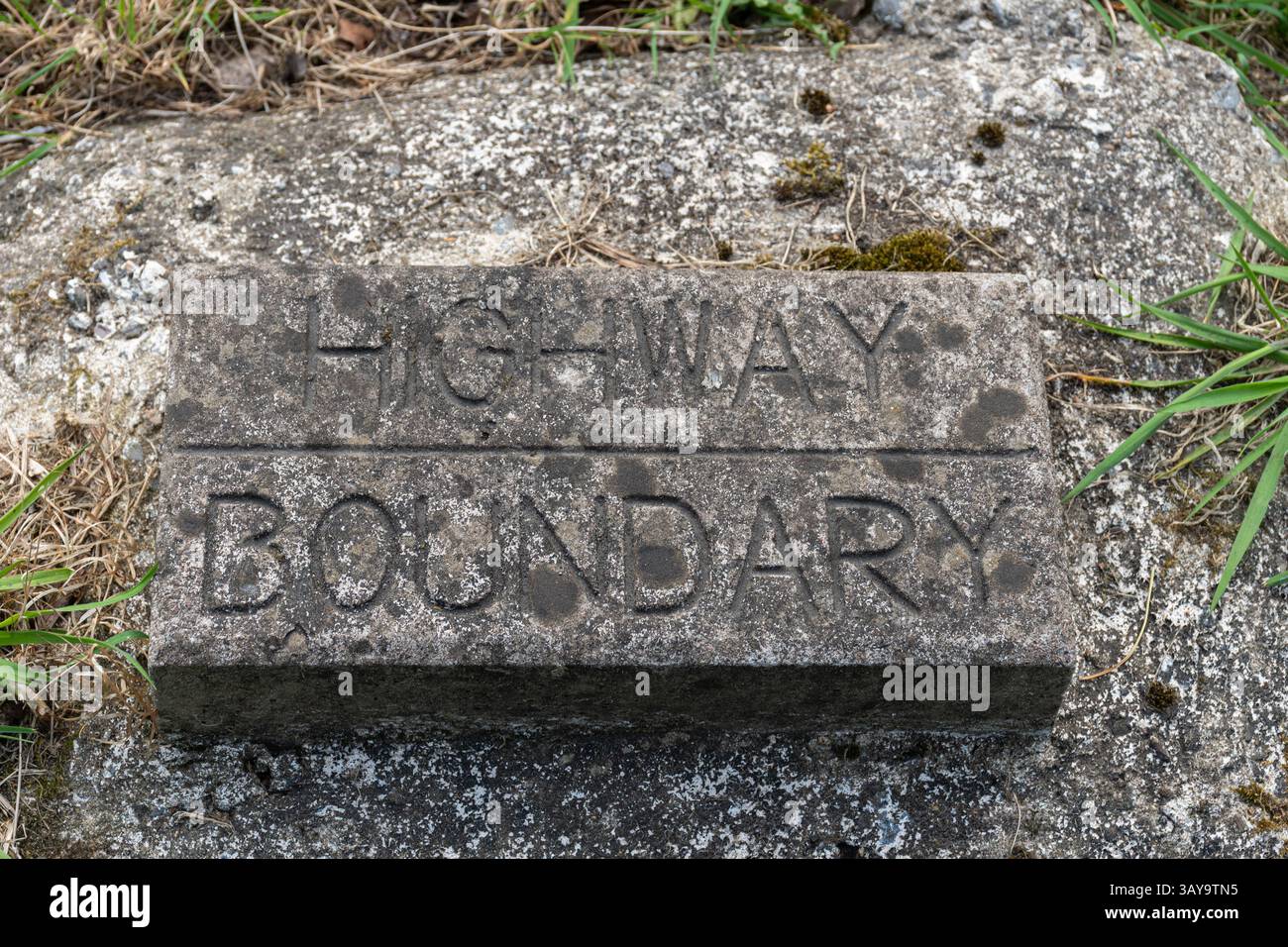 Highway boundary marker stone on a public road grass verge, Hampshire ...