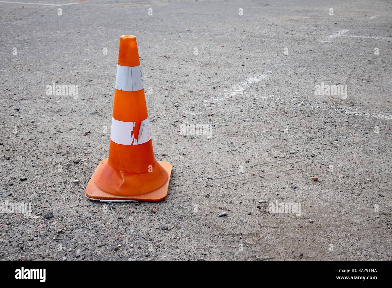 Orange traffic cones stand as a warning sign on the asphalt road ...