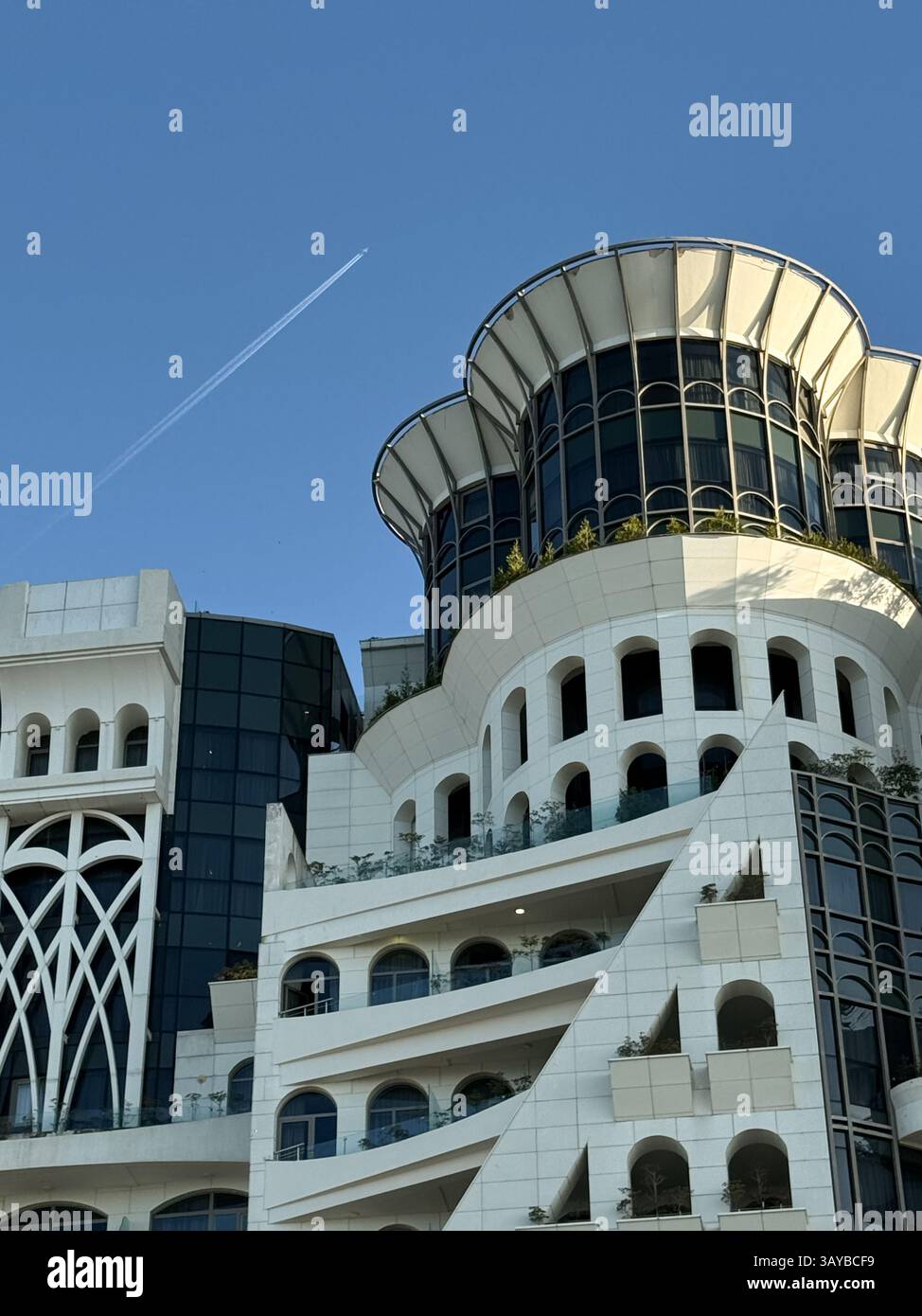 The photo shows a modern multi-story building featuring white stone and ...