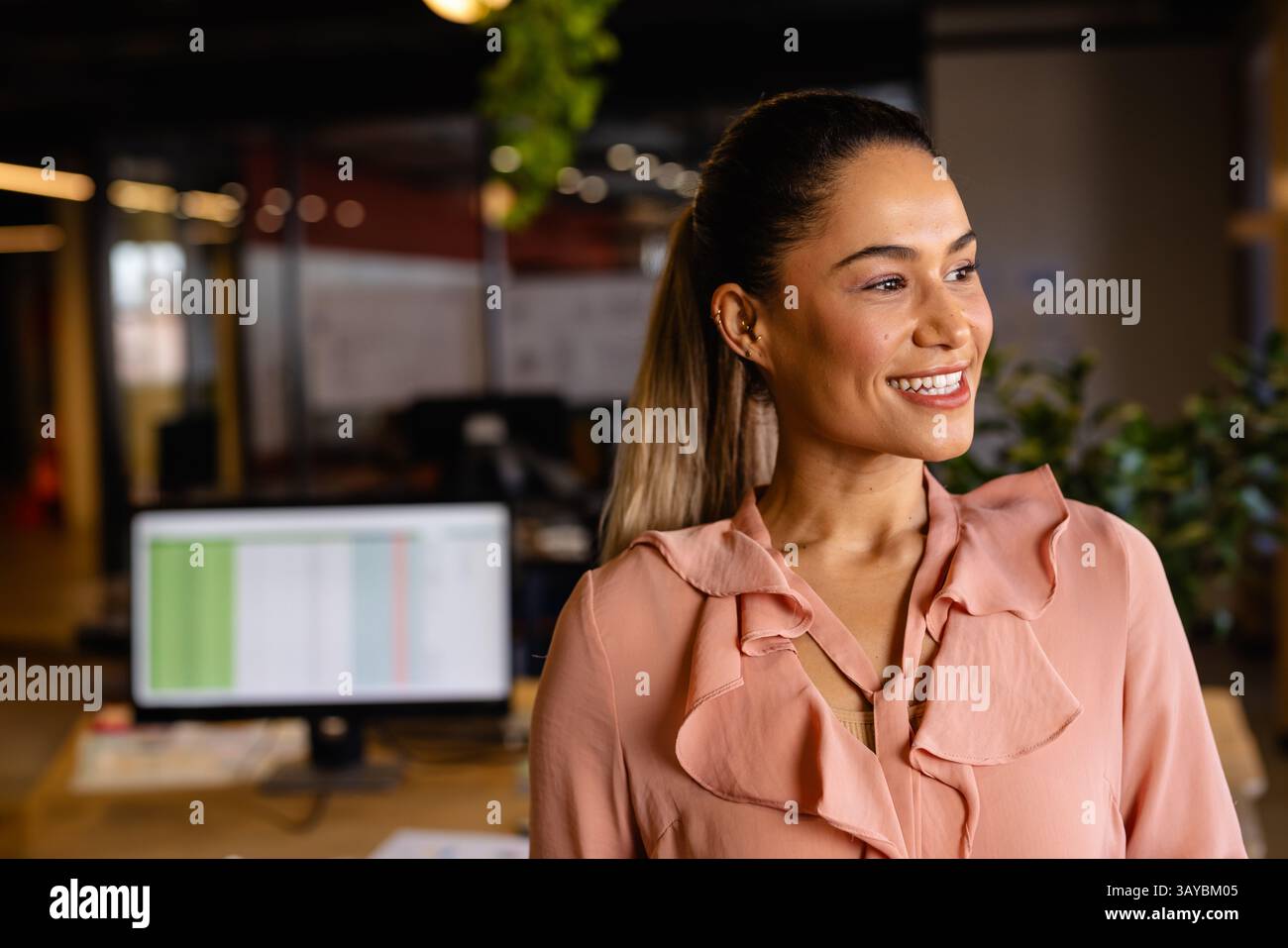 Professional woman smiling and looking in open-plan office with ...