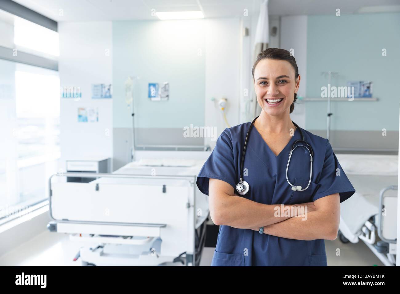 female nurse standing with arms crossed and smiling in hospital ward ...