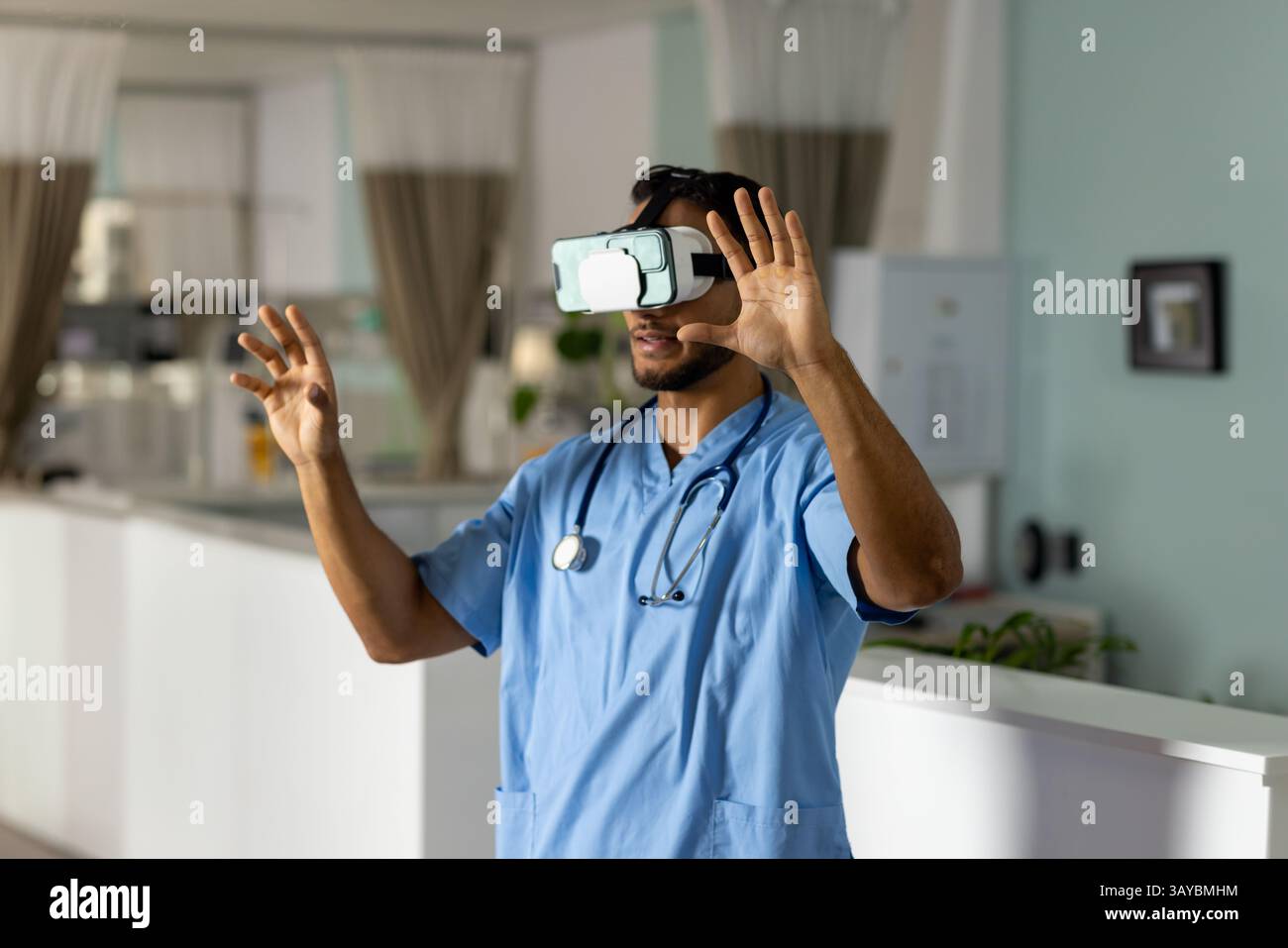 Male nurse using virtual reality headset and raising hands at reception ...