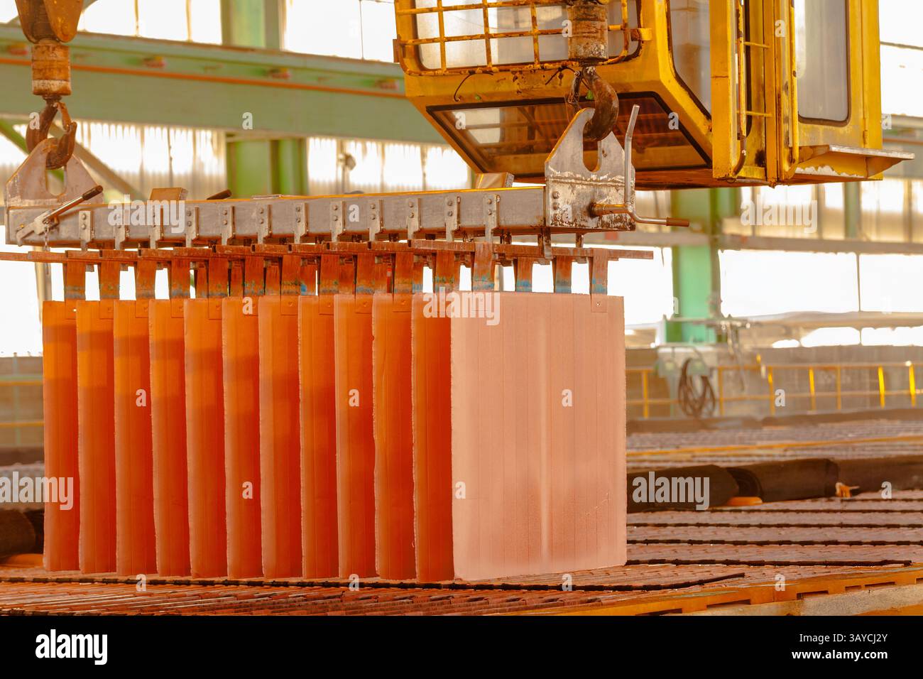 Close-up of copper cathodes hanging from a crane in an electrowinning ...