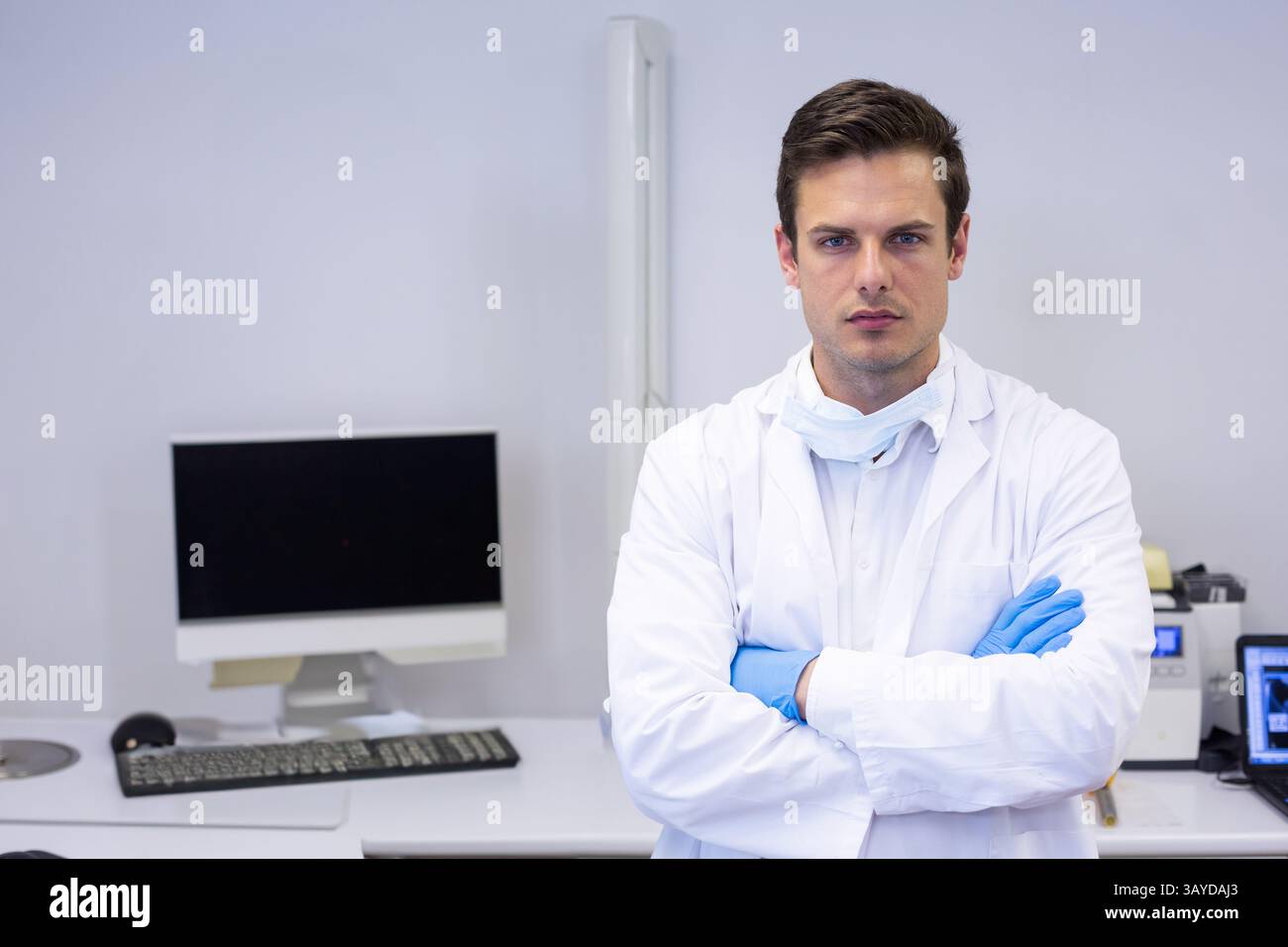 young man standing with arms crossed in lab office, with computer ...