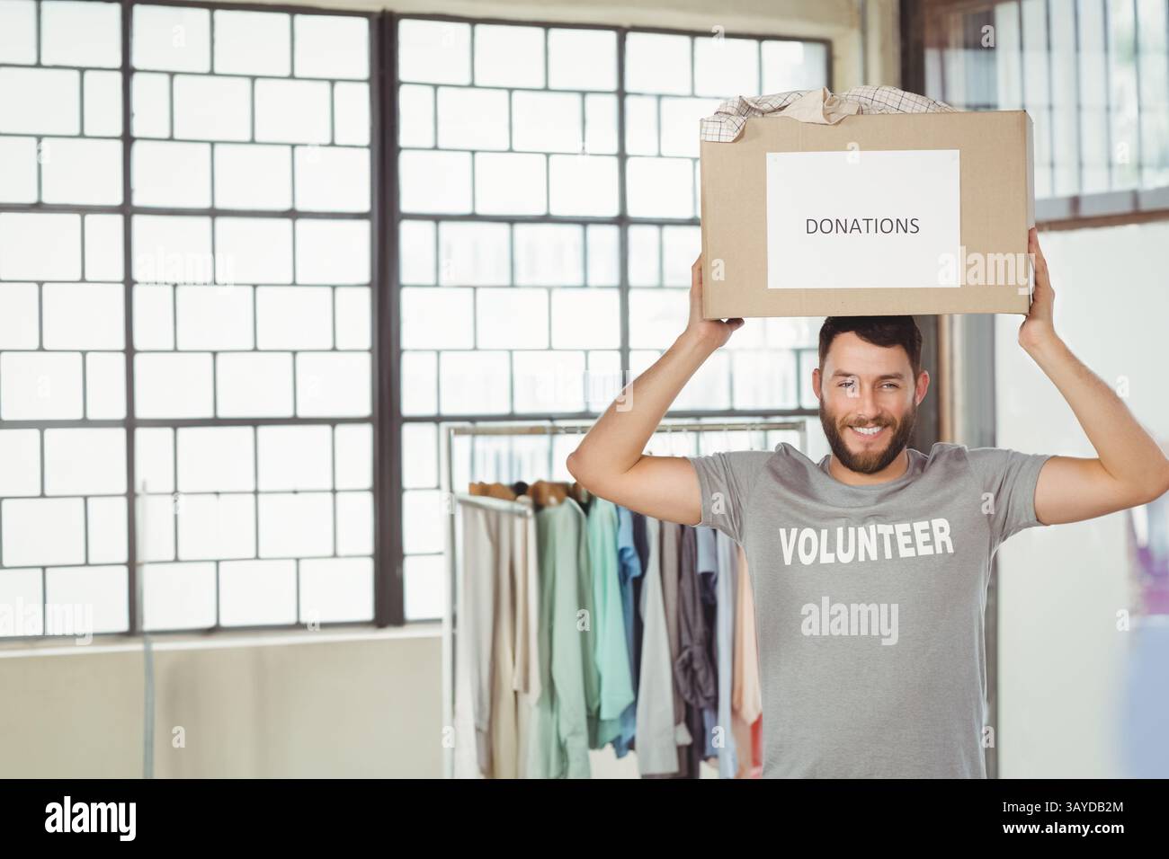 Male volunteer holding donations box overhead in indoor donation center ...