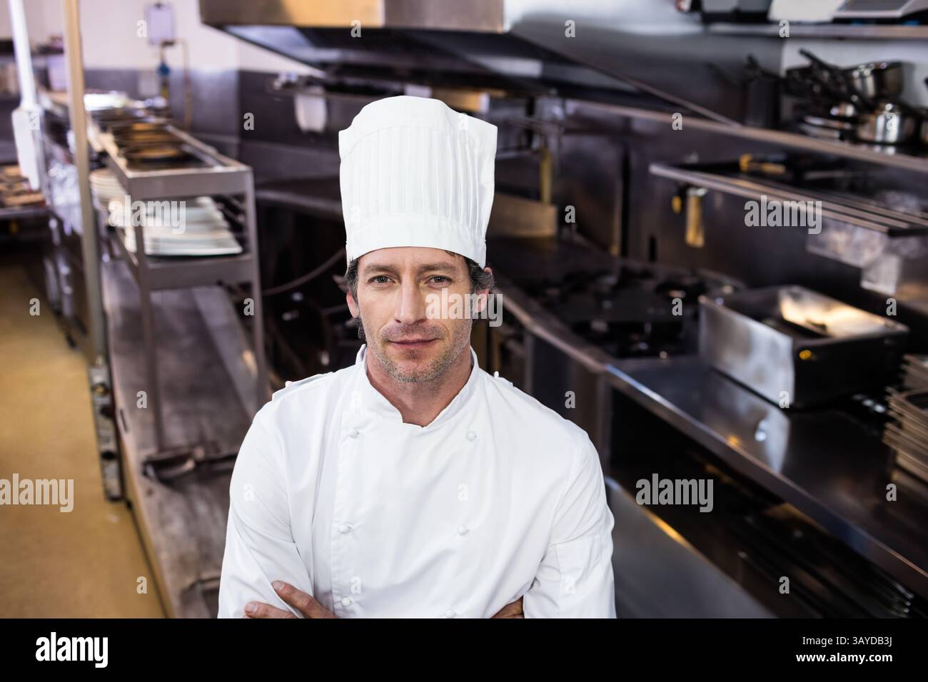 Male chef wearing coat and hat, working in commercial kitchen with ...