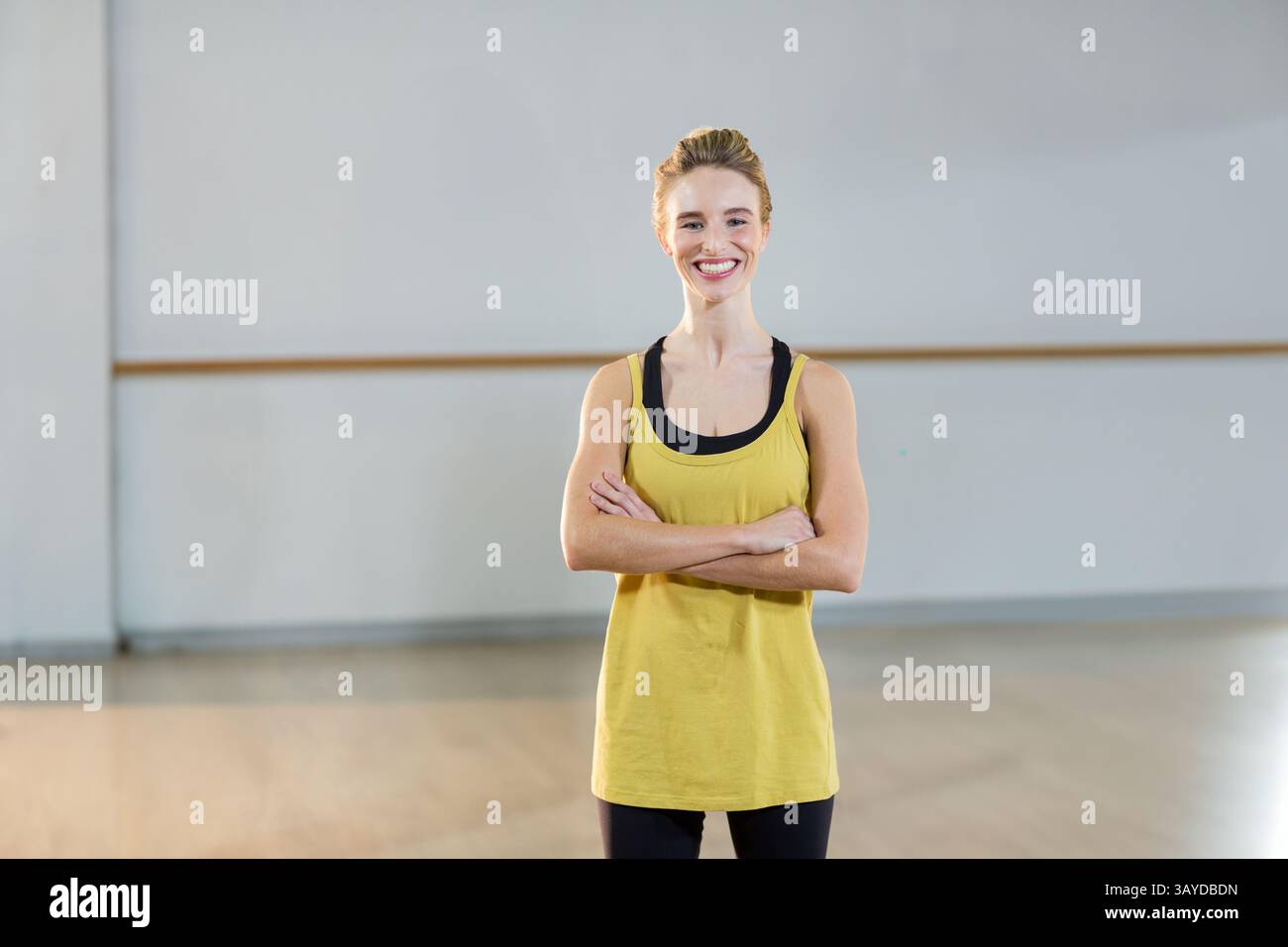 Young woman smiling and standing with crossed arms in dance studio ...
