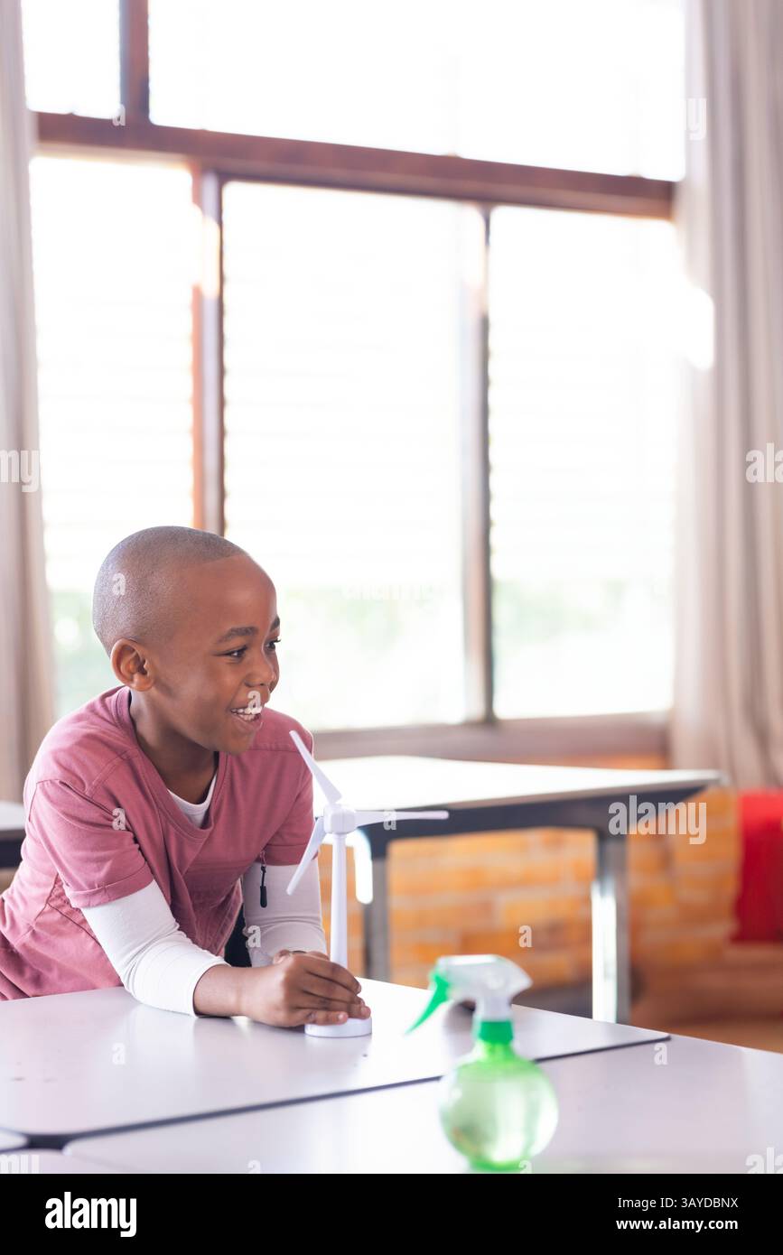 African American boy sitting at classroom desk interacting with model ...