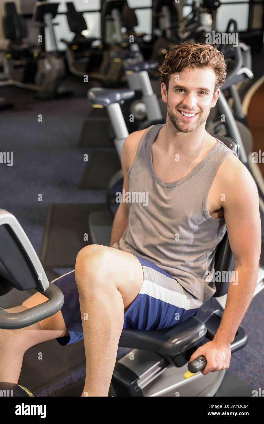Man riding recumbent bike in gym, gripping handles with digital console ...