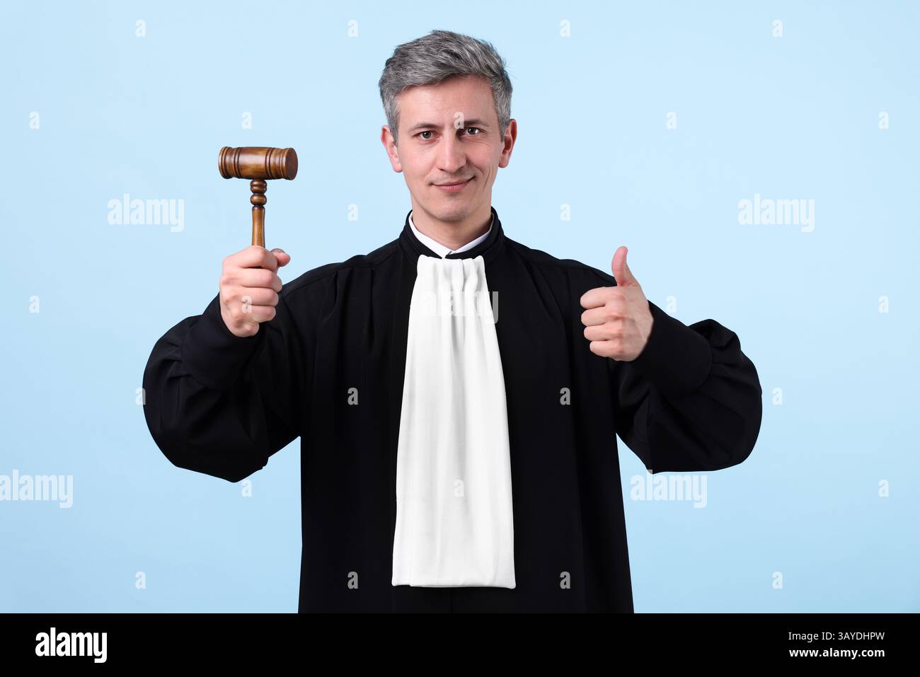 Judge with mallet showing thumbs up on light blue background Stock ...