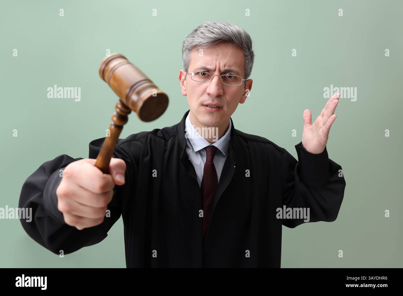 Emotional judge with mallet on green background Stock Photo - Alamy