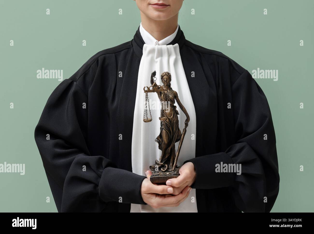 Judge with figure of Lady Justice on light green background, closeup ...