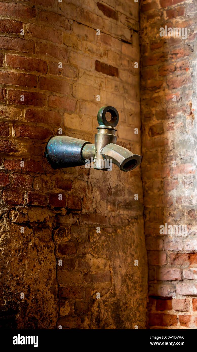 An antique metal spout juts from scarred brick, evoking an industrial ...