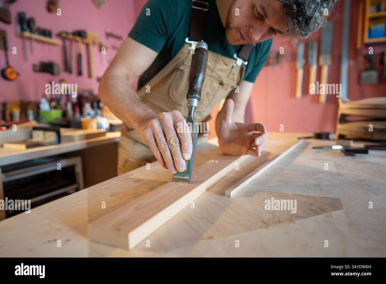 Skilled serious craftsman carpenter meticulously refining board texture ...