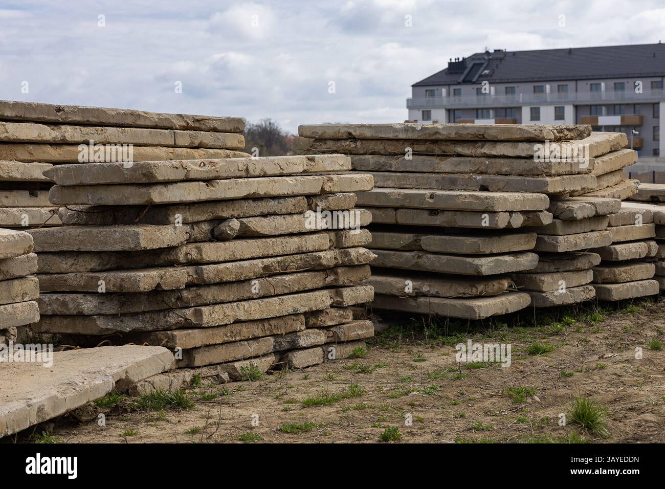 Stacks of old weathered concrete slabs at construction site with modern ...