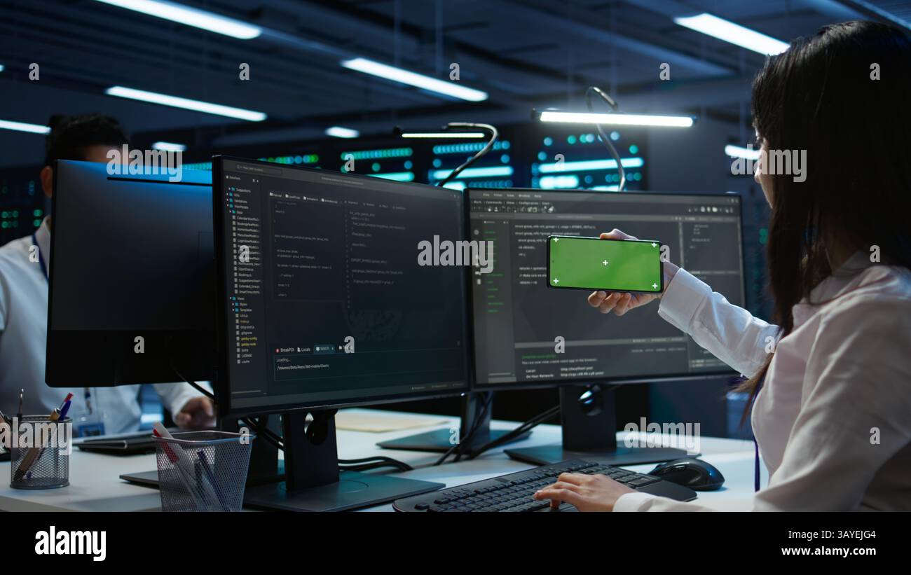 Technician using mockup mobile phone in data center, managing servers. Expert in server hub ...