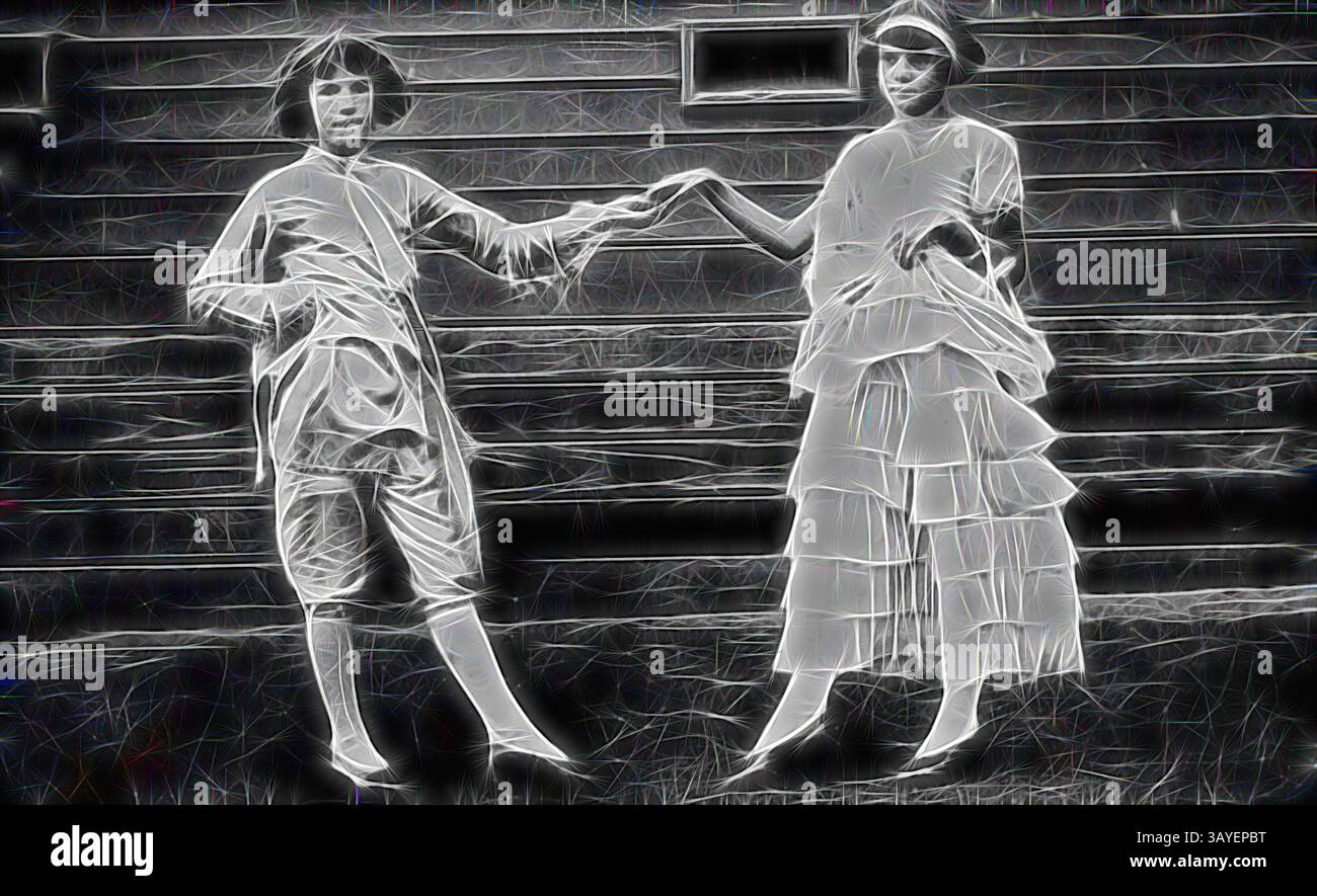 Two women stand close together in a playful pose, one extending a hand ...