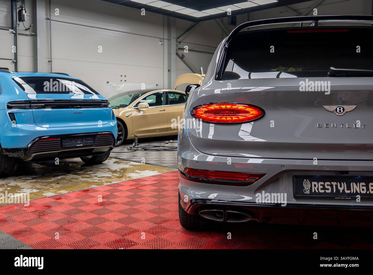 Gray Bentley Bentayga with illuminated rear lights, blue Porsche Macan ...