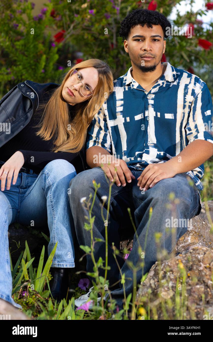 Stylish young couple sitting together in a garden, enjoying a peaceful ...