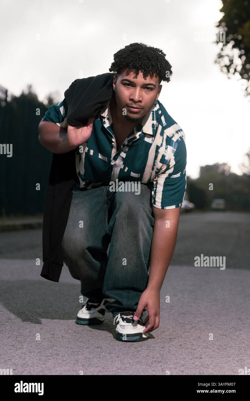 Confident Young Man Crouching on Urban Street Holding Jacket Over ...