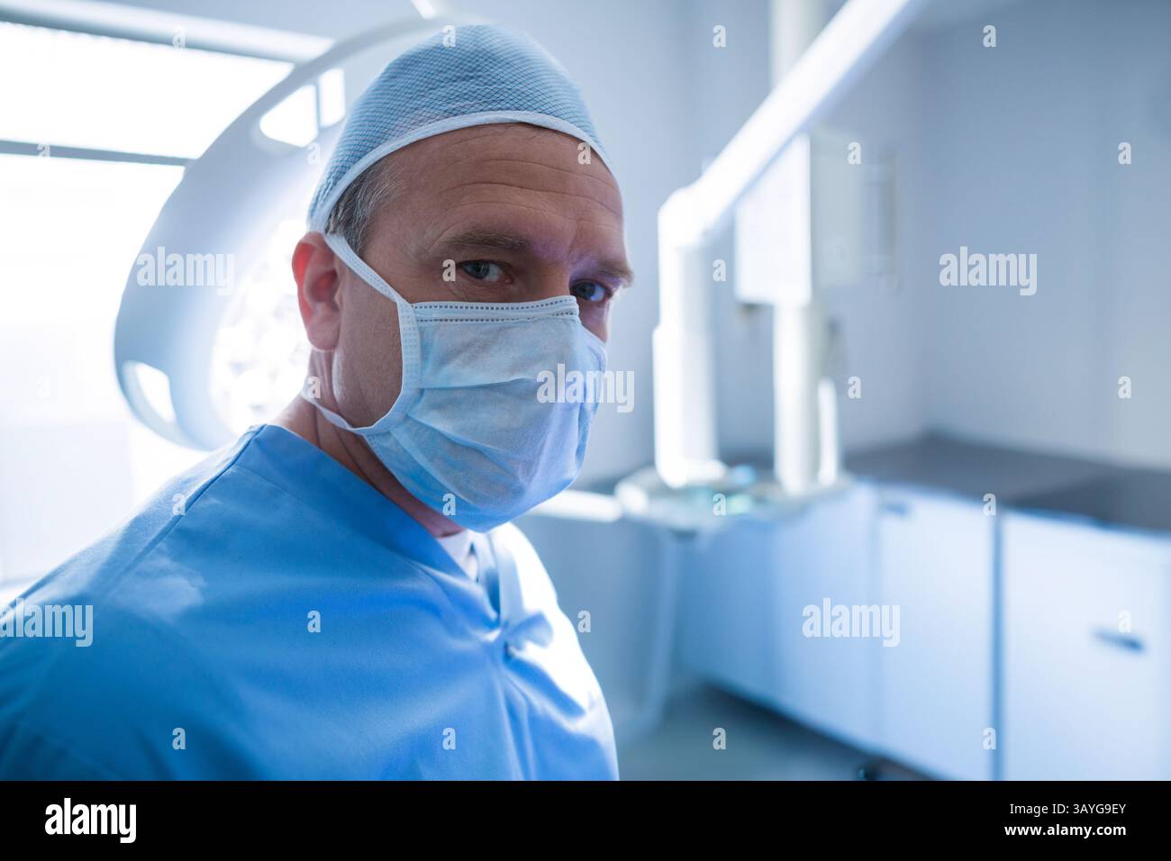 male surgeon standing in hospital operating room with overhead light ...