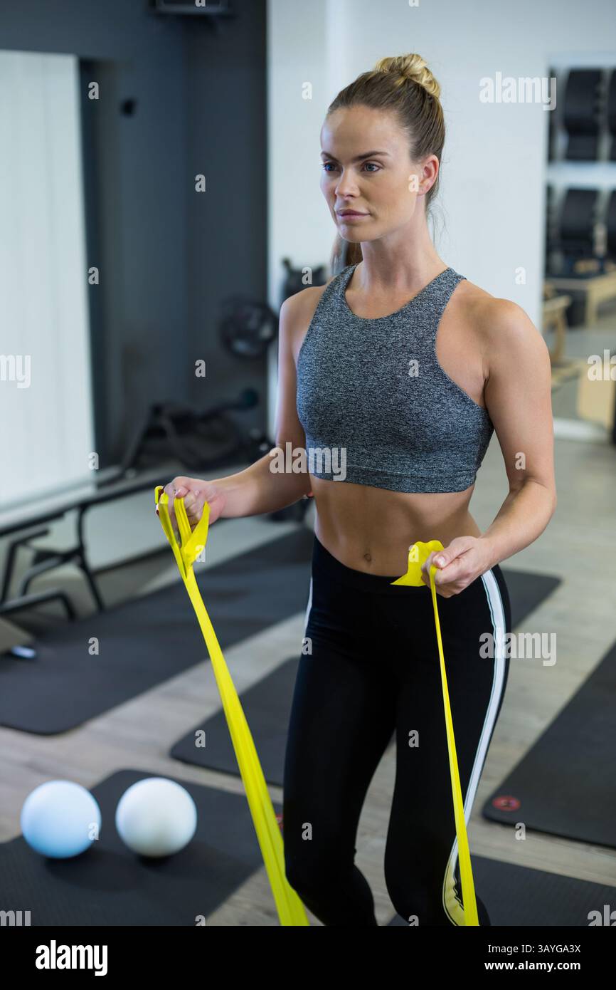 Woman performing resistance band workout in modern gym, holding yellow ...