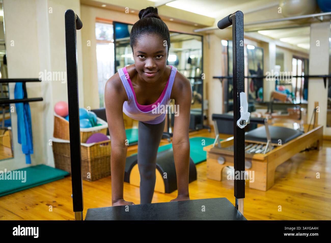 African American woman leaning forward on reformer tower in Pilates ...