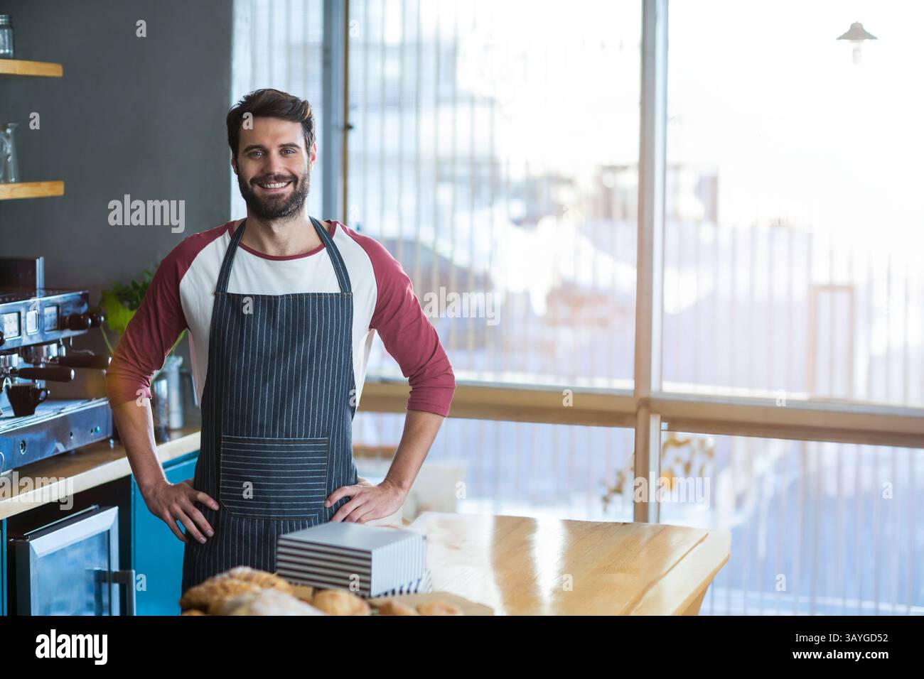 Man standing behind counter in cafe, arranging loaves of bread and ...