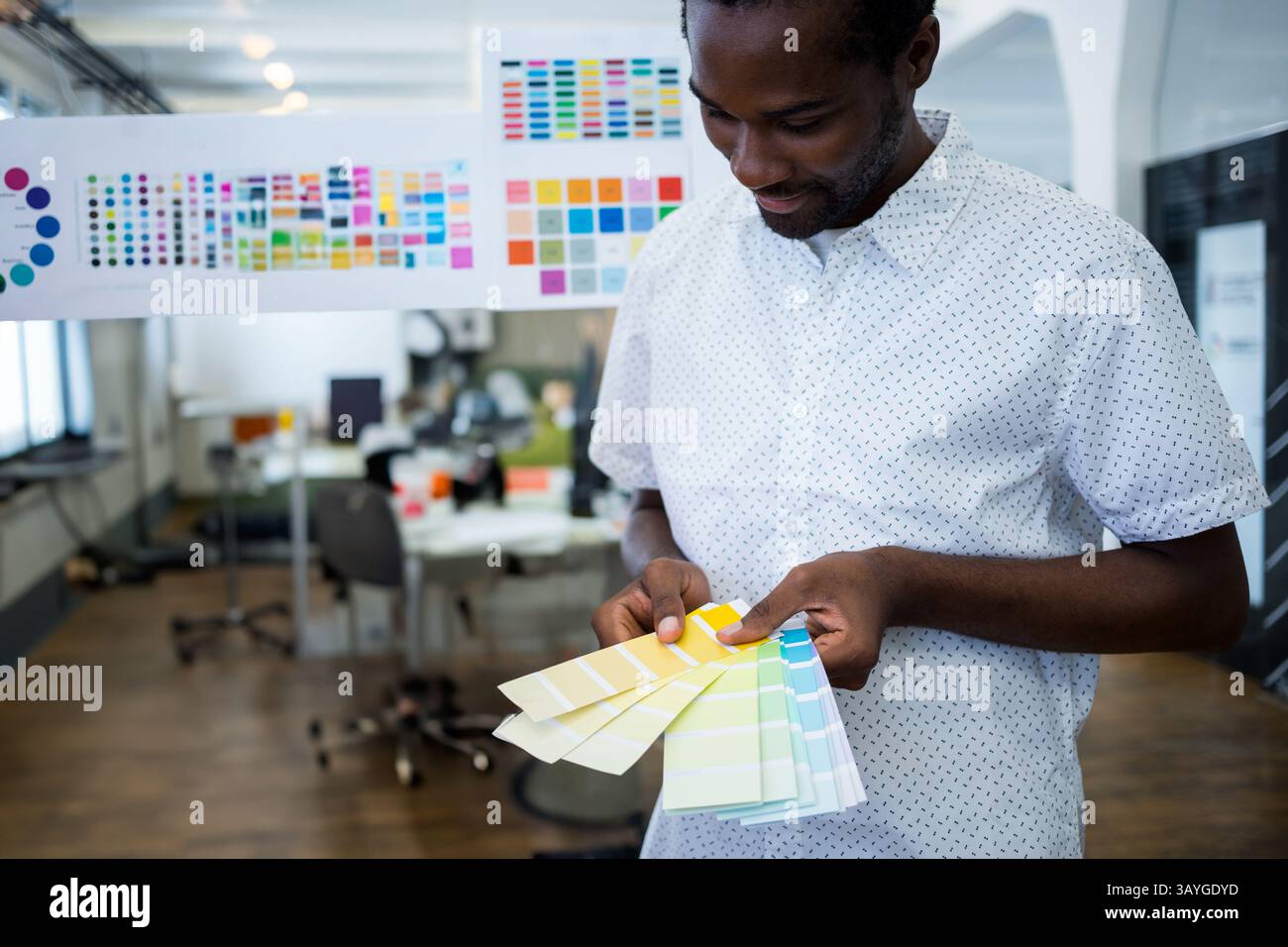 African American man examining paint swatches in design studio, with ...